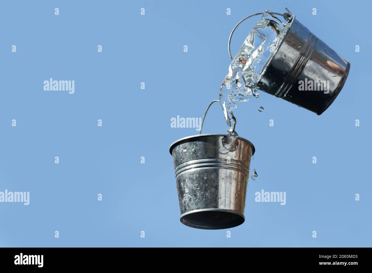 A pouring water from falling bucket to bucket, on a background of blue ...