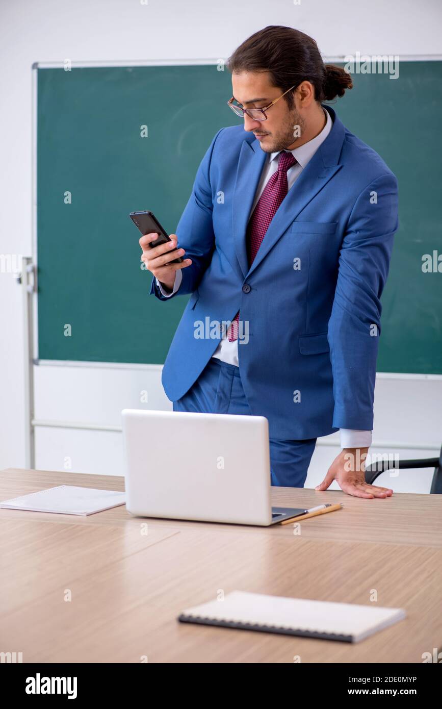 Young teacher in suit in front of green board Stock Photo - Alamy