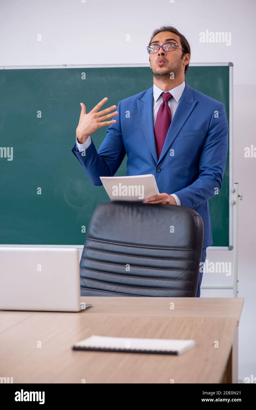 Young teacher in suit in front of green board Stock Photo - Alamy