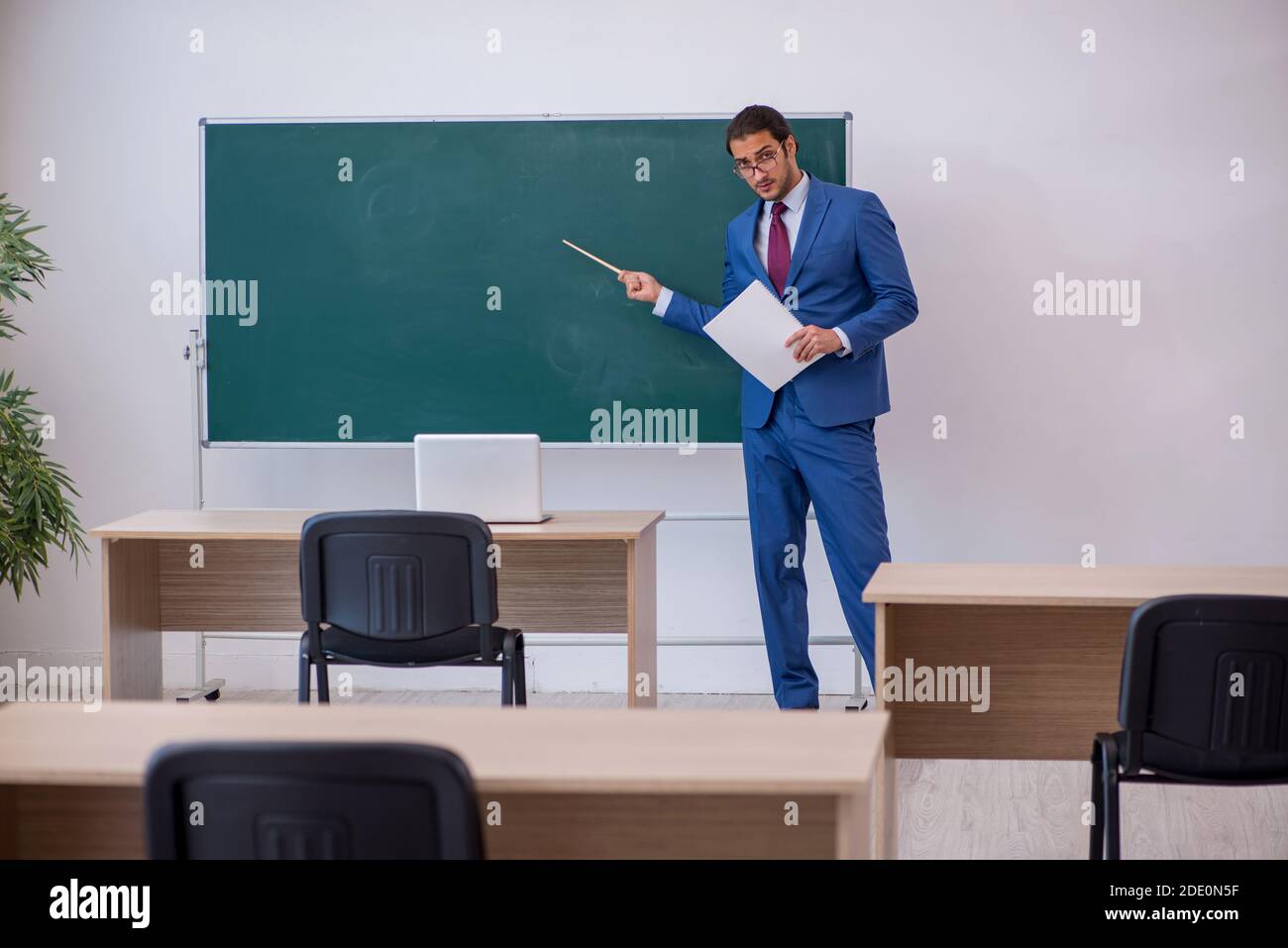 Young teacher in suit in front of green board Stock Photo - Alamy