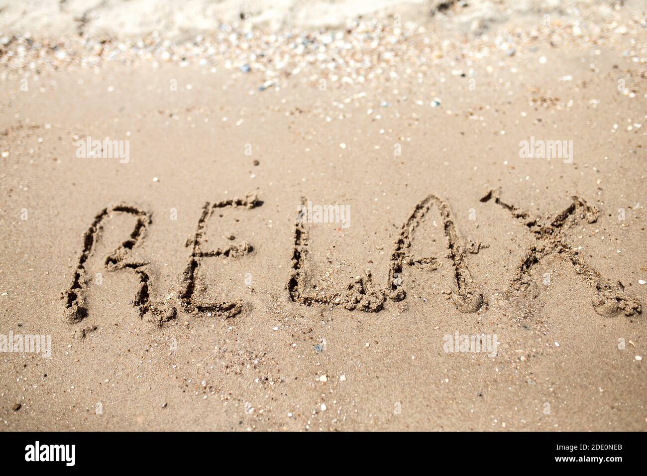 Handwritten Relax Word on the Sand Coast. Wonderful words on beach sand ...