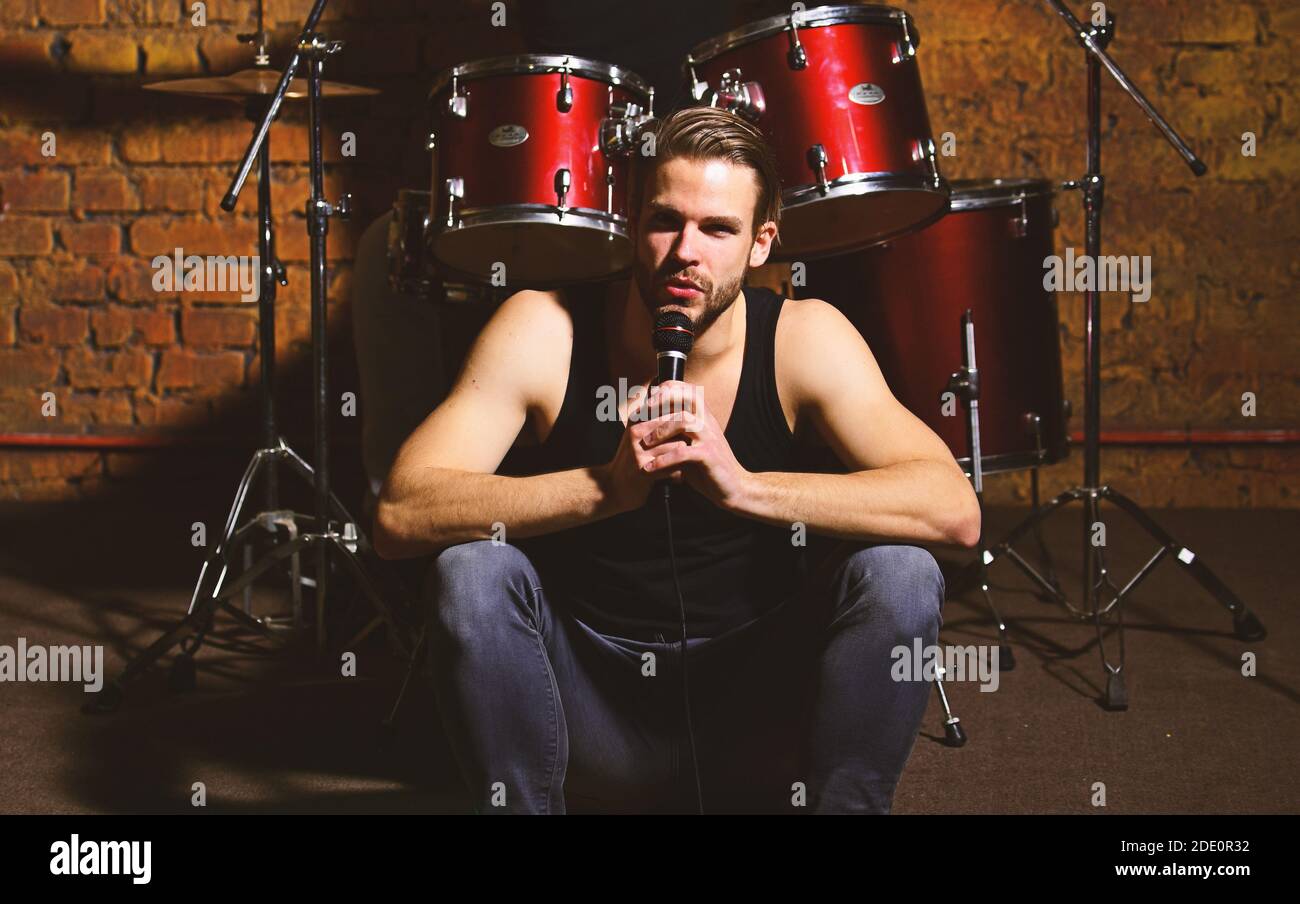 Singer or star holds microphone sitting on scene and sings. Pop music ...