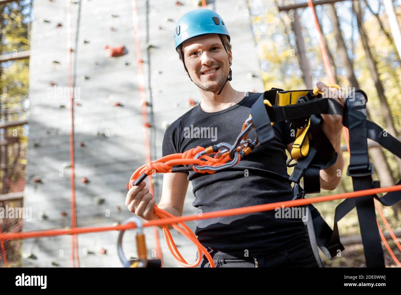 Handsome man wearing safety equipment for climbing at amusement park ...