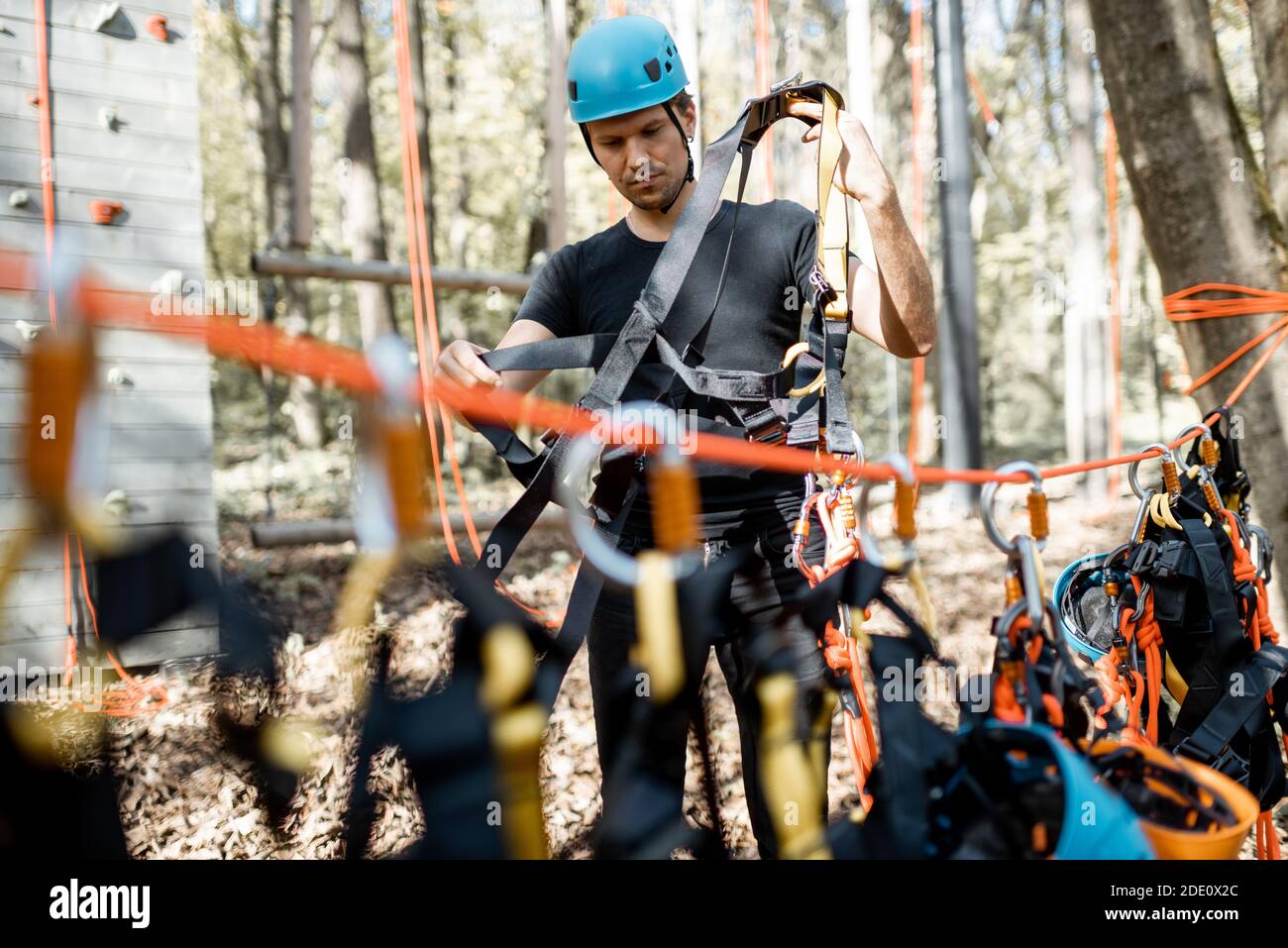 Handsome man wearing safety equipment for climbing at amusement park ...