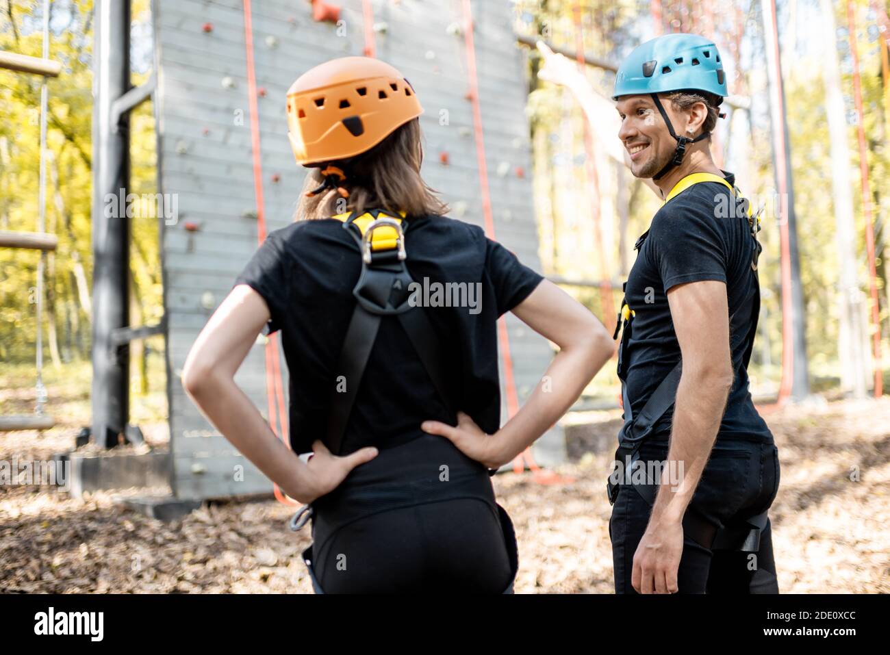 Well-equipped man and woman standing in front of the climbing wall ...