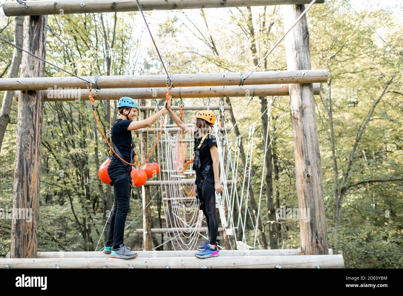 Well-equipped man and woman having an active recreation, climbing ropes ...