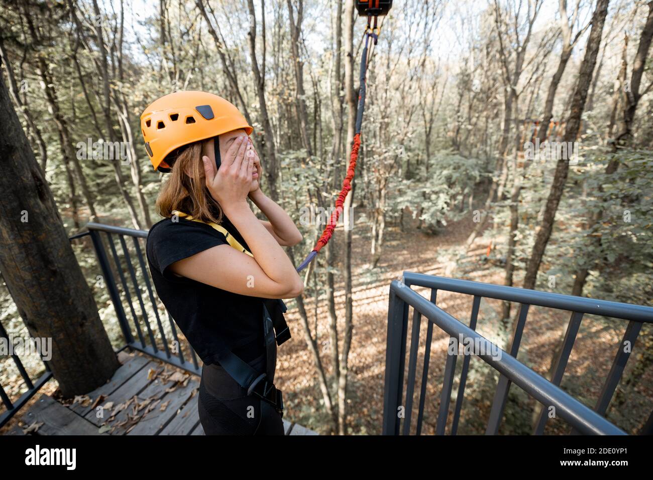 Young woman feeling frightened, closing eyes before a bungee jump from ...