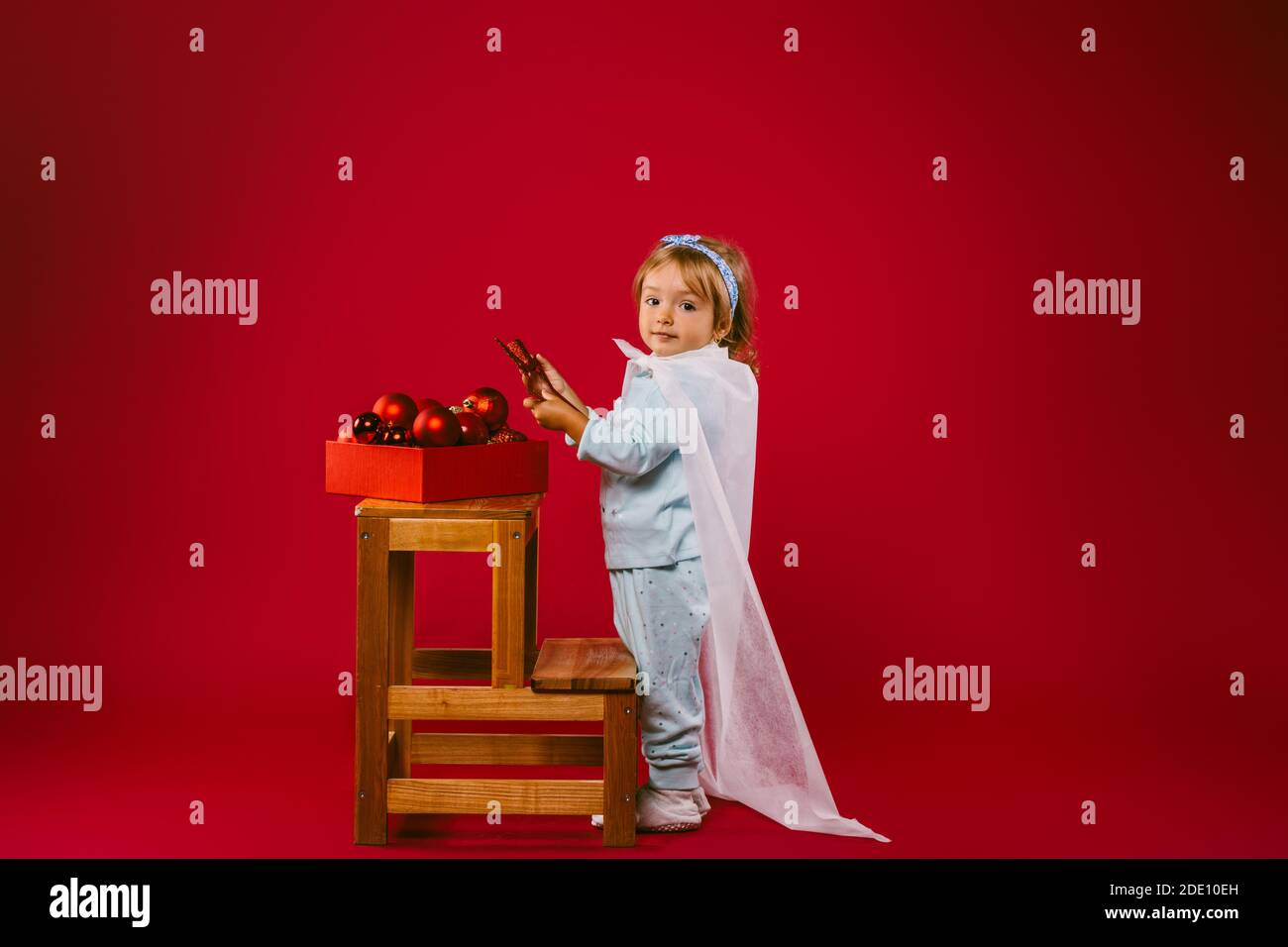A girl in pajamas with a homemade superhero cape holding a red star by ...