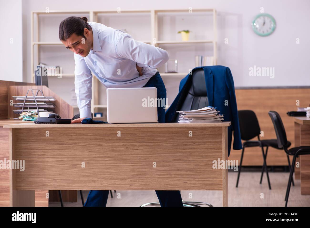 Young employee suffering from backpain at workplace Stock Photo - Alamy