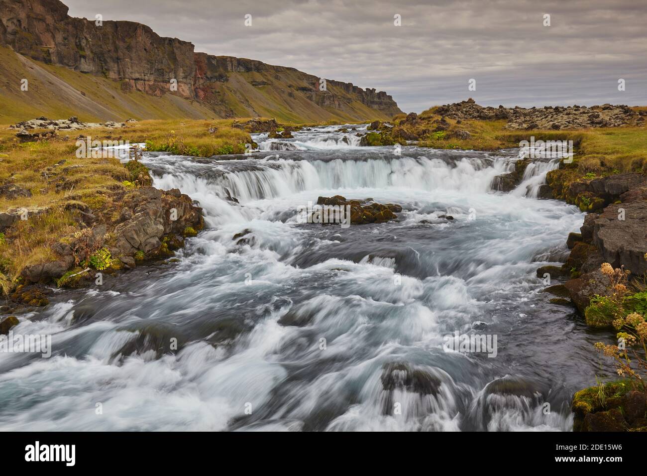 A classic Icelandic landscape, a river flowing along the base of a ...