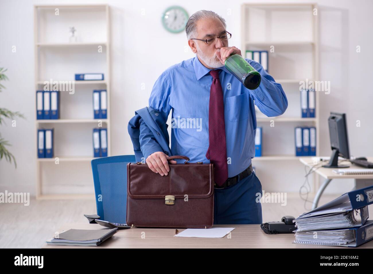 Senior male employee drinking alcohol in the office Stock Photo - Alamy