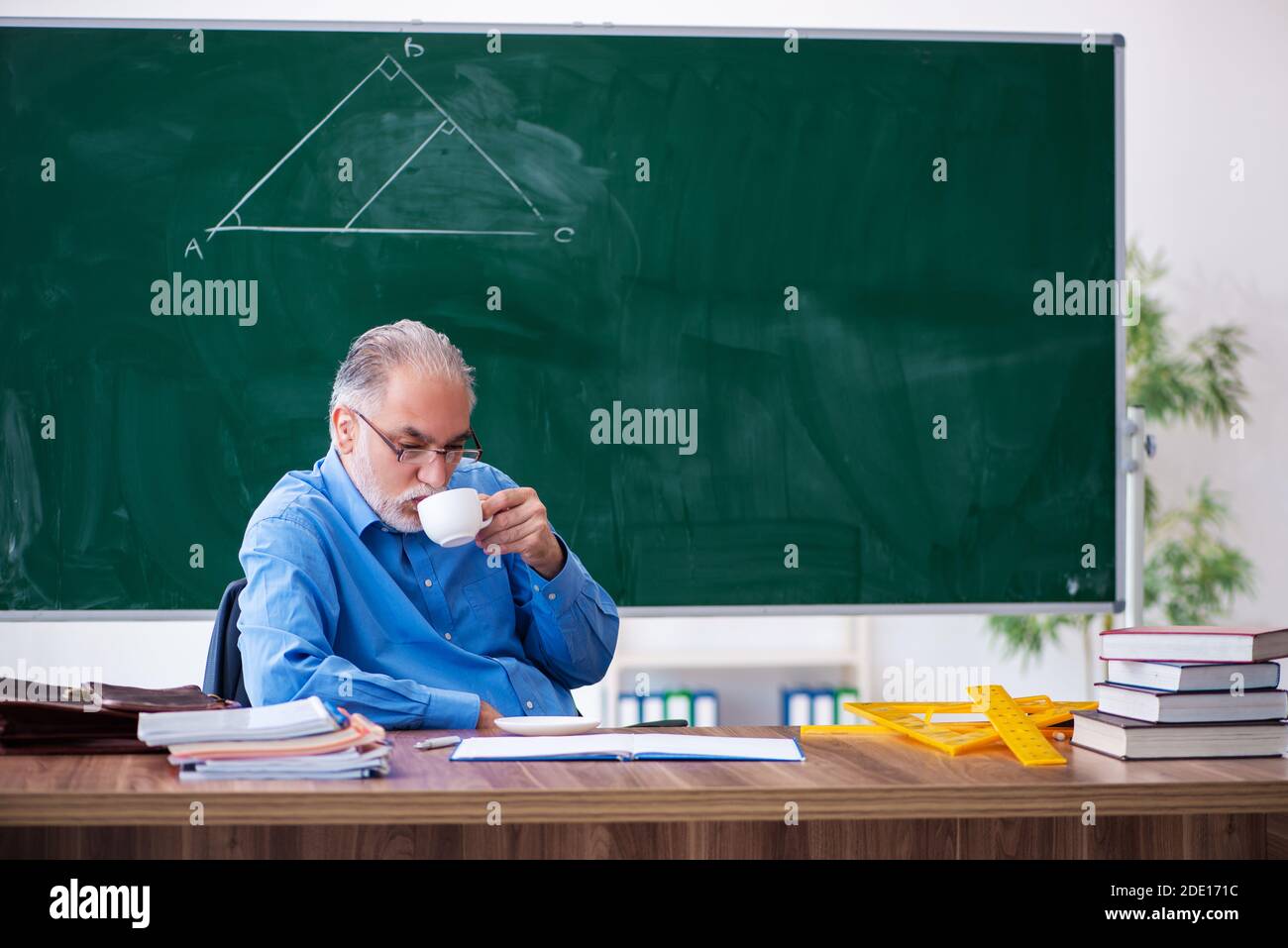 Aged male math teacher in the classroom Stock Photo - Alamy