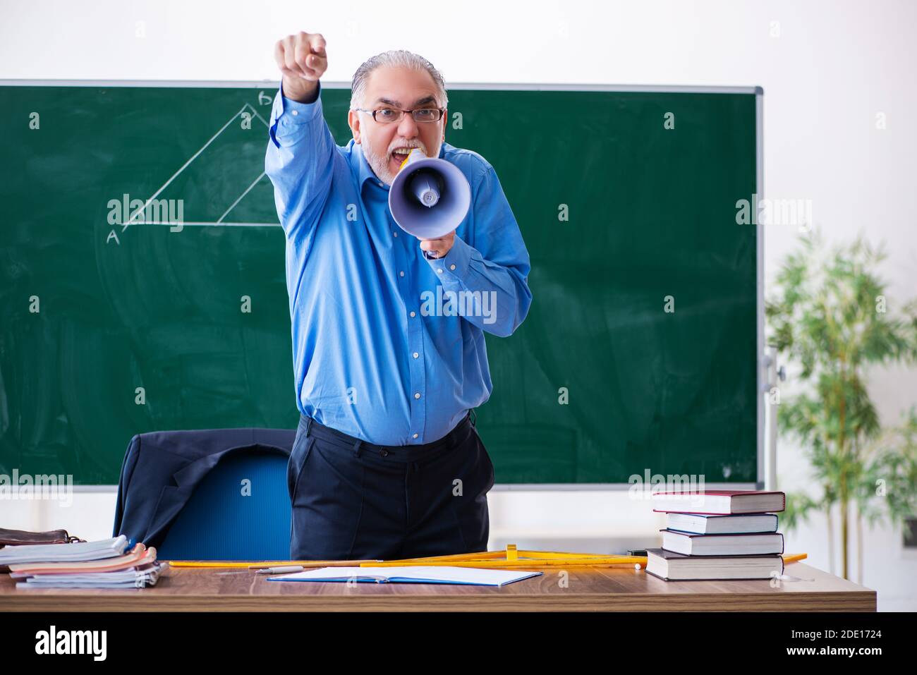 Angry male math teacher holding megaphone Stock Photo - Alamy