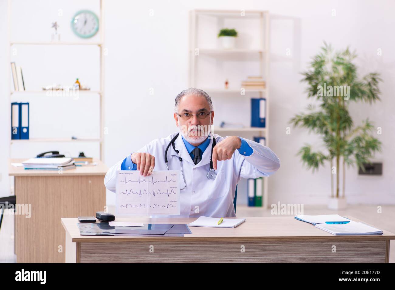 Senior male doctor cardiologist looking electrocardiogram Stock Photo ...