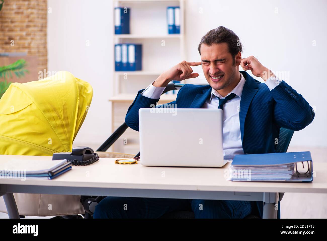 Young employee looking after kid at workplace Stock Photo - Alamy