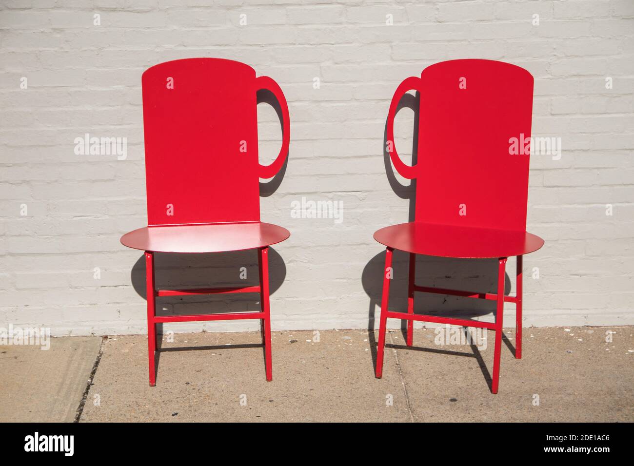 Two red chairs and a off white brick wall Stock Photo - Alamy