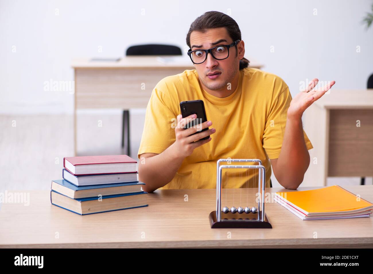 Young student holding mobile phone during exam preparation Stock Photo ...