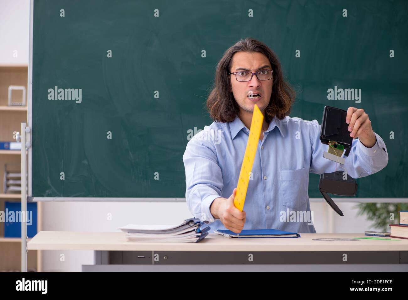 Young teacher in front of green board Stock Photo - Alamy