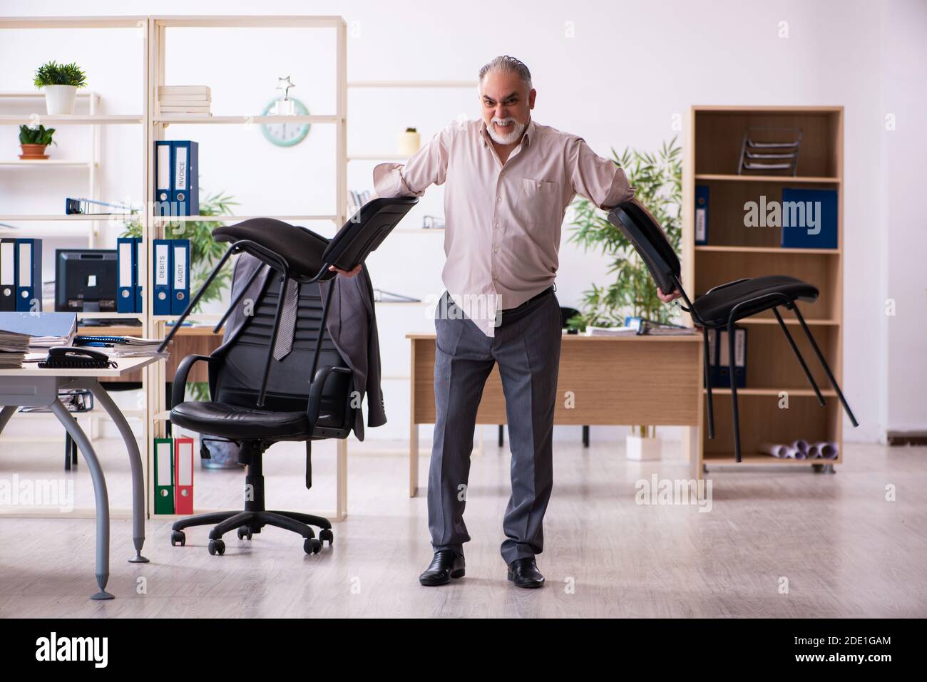 Senior male employee doing physical exercises at workplace Stock Photo ...