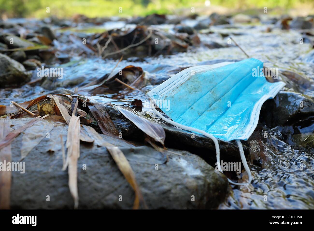 Littered and floating used surgical face mask garbage on a river. Water ...