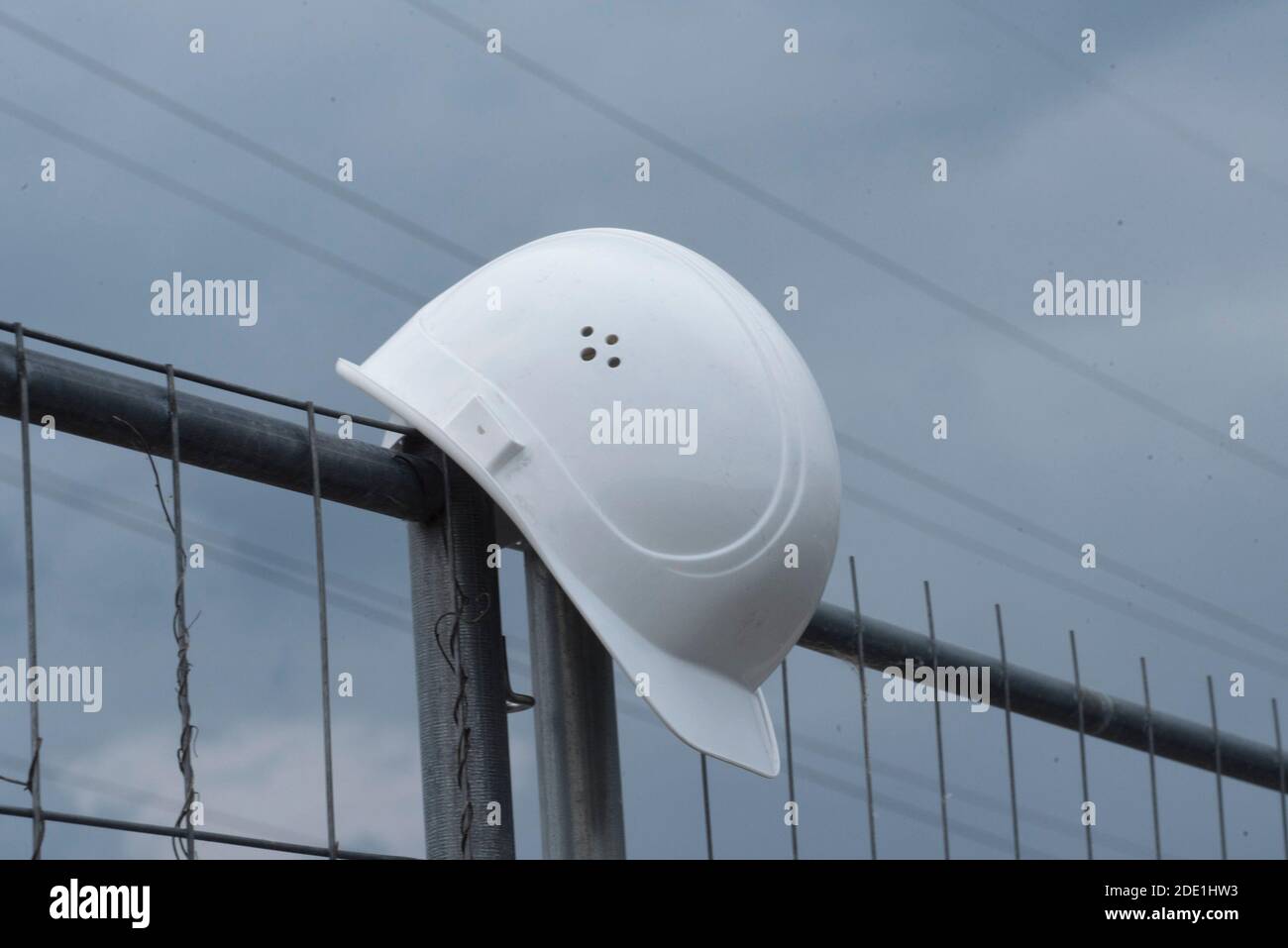 Safety helmet hanging on fence, gray and cloudy sky background Stock ...