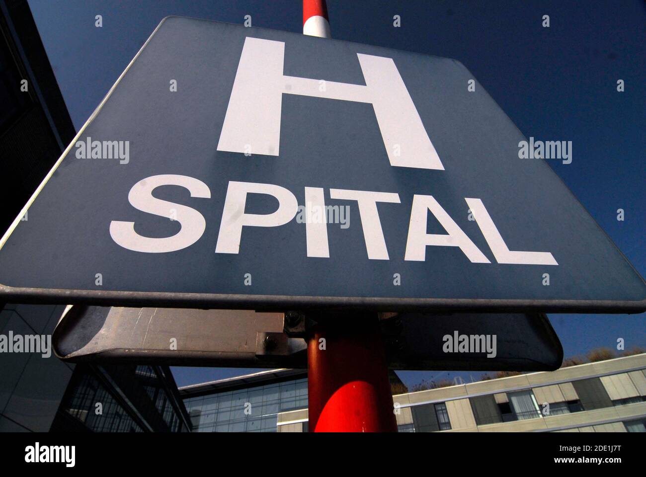 blue hospital sign on the street, hospital building in the background ...
