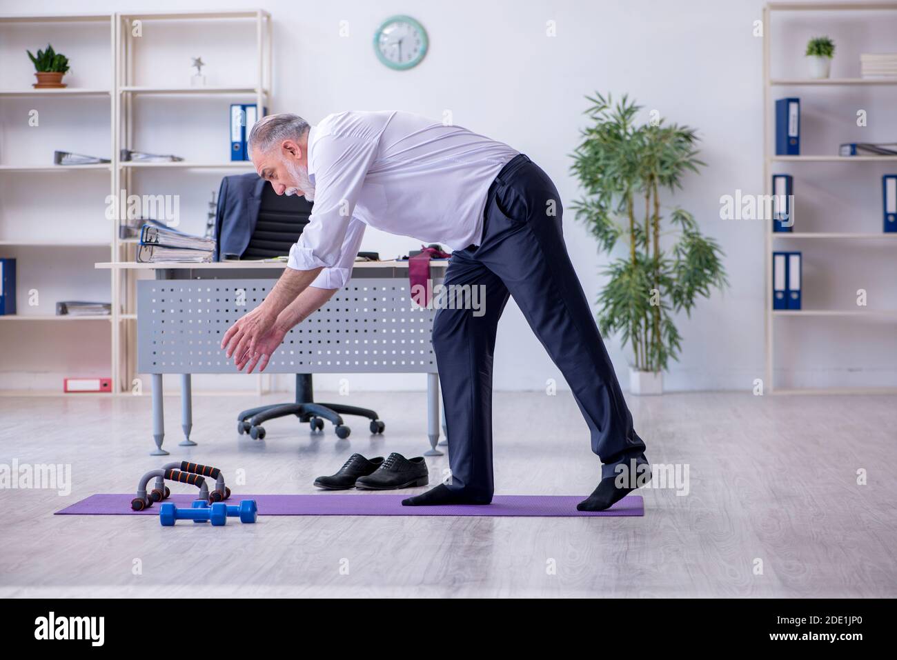 Aged employee doing physical exercises during break Stock Photo - Alamy