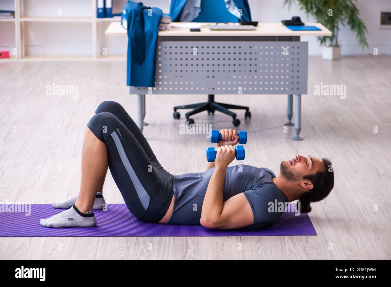 Young male employee doing sport exercises in the office Stock Photo - Alamy