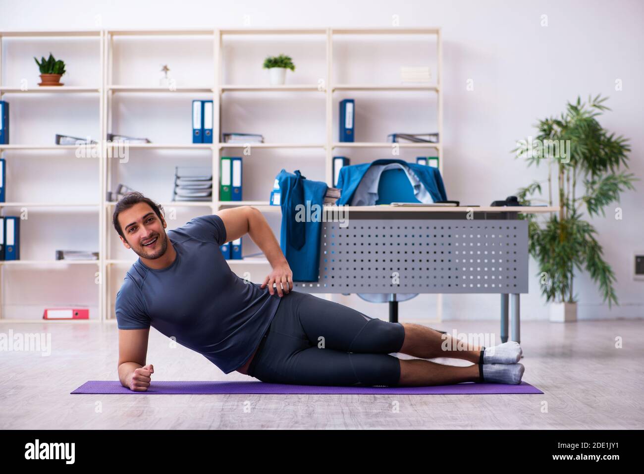 Young male employee doing sport exercises in the office Stock Photo - Alamy