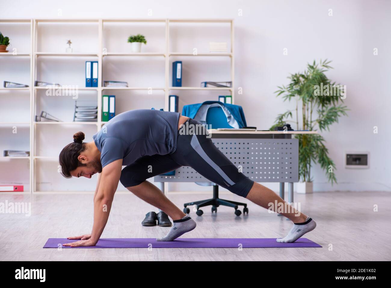 Young male employee doing sport exercises in the office Stock Photo - Alamy