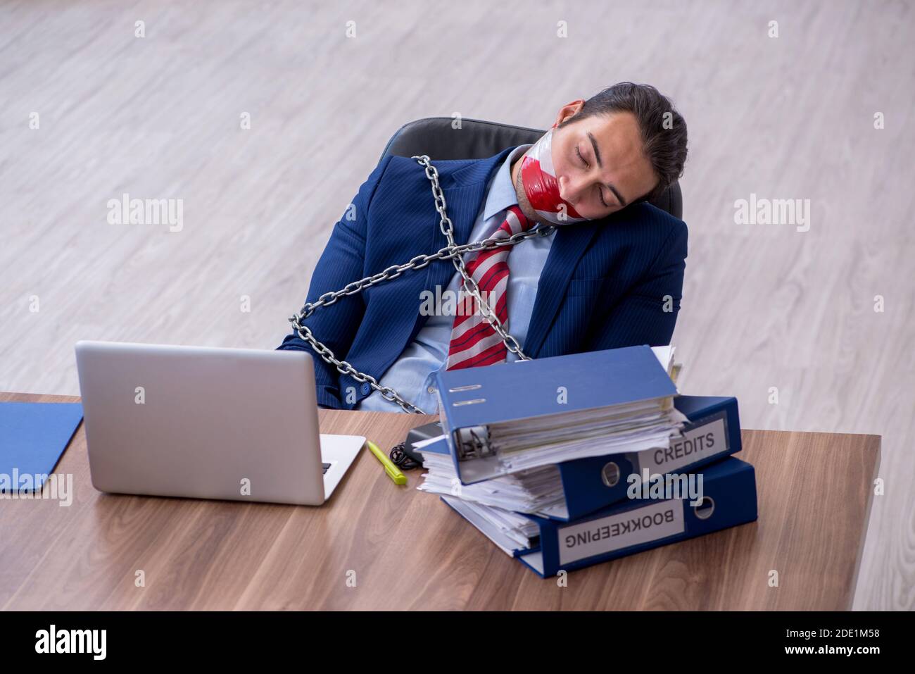 Chained employee unhappy with excessive work in the office Stock Photo ...