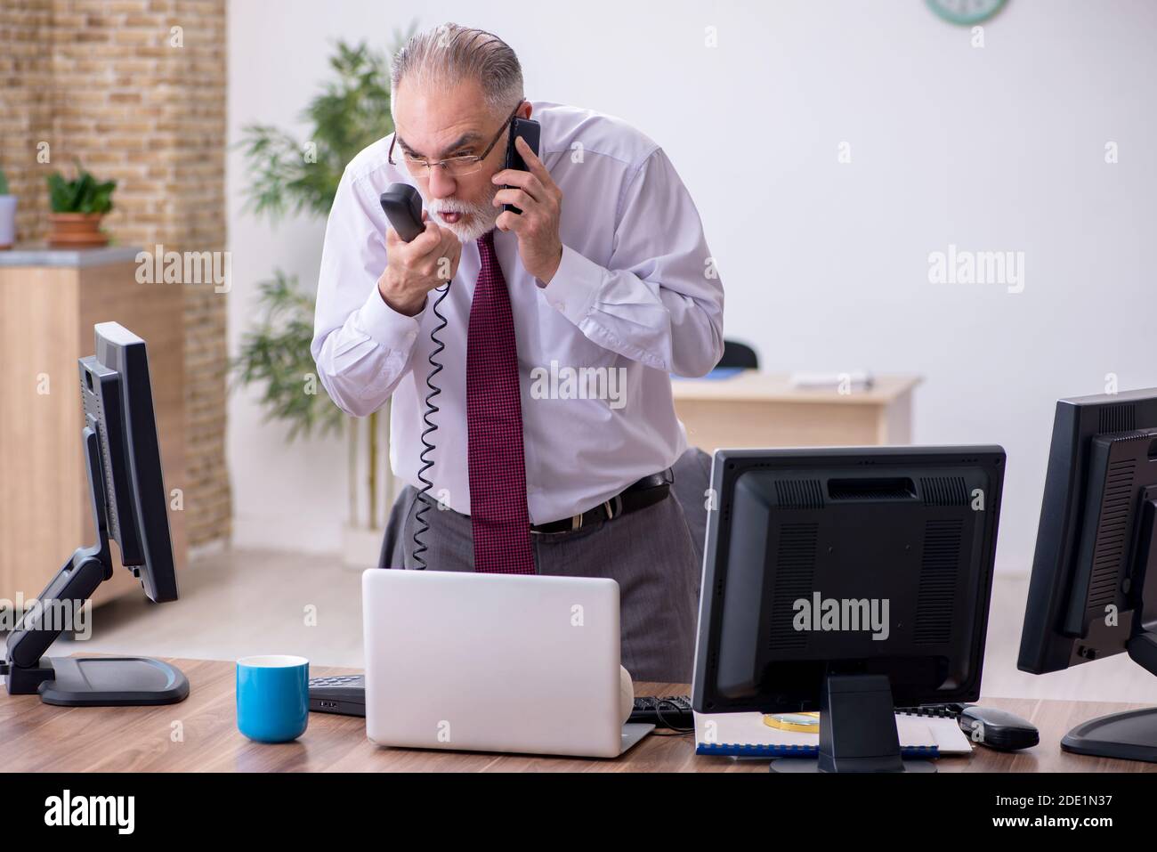 Old boss sitting at desktop in the office Stock Photo - Alamy