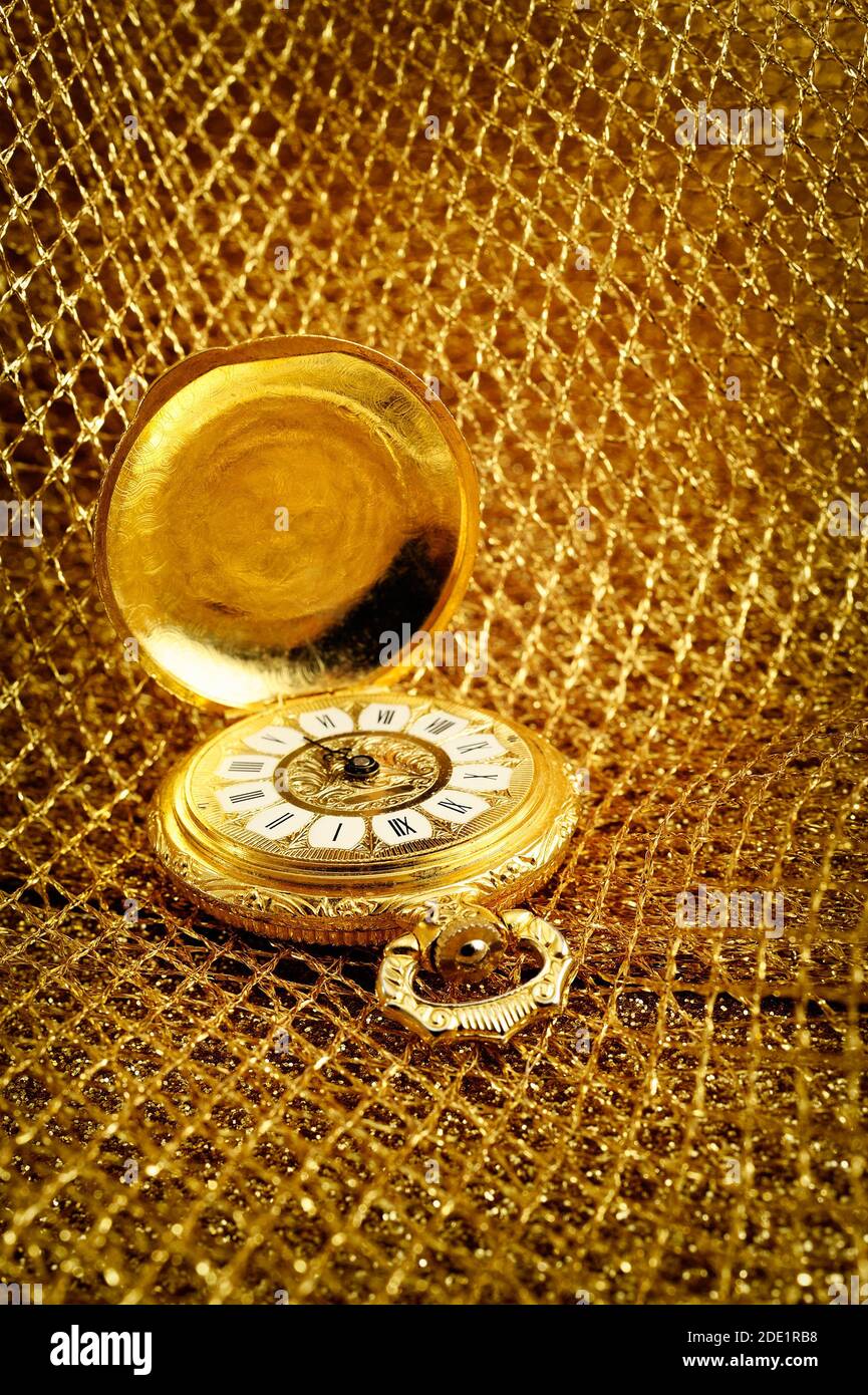 Old gold pocket watch laying on golden sparkling grid Stock Photo - Alamy