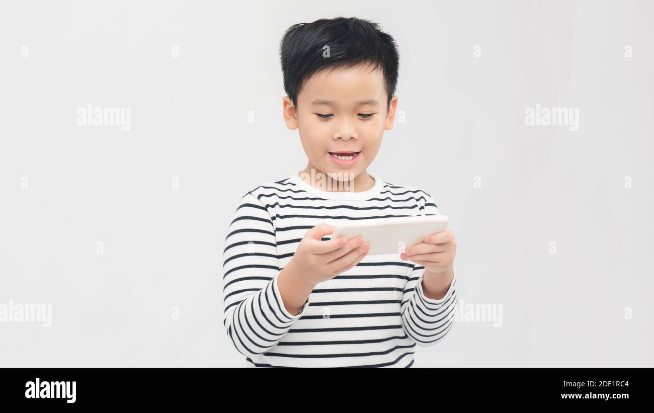 Portrait of an amused cute little kid playing games on smartphone ...