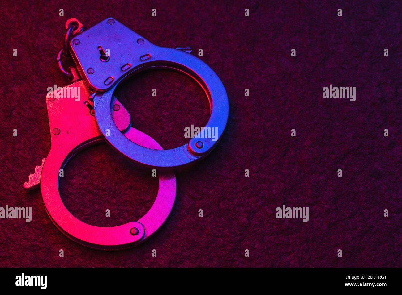 Handcuffs on dark background illuminated by flashing lights of police ...