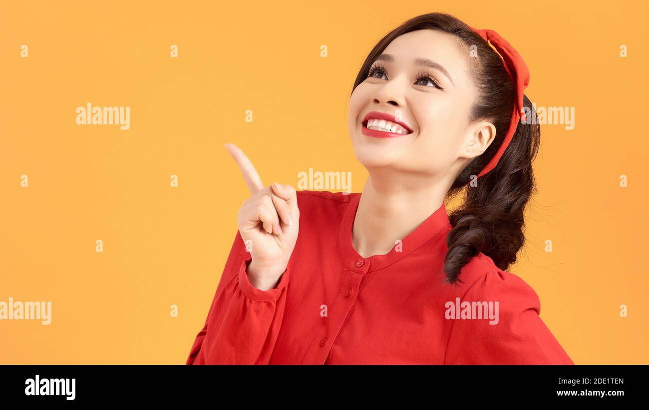 Image of happy young lady standing isolated over yellow background. Looking camera pointing ...