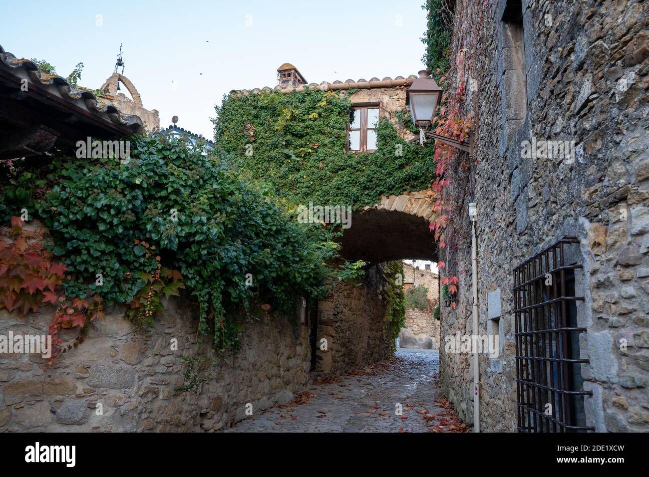 Medieval alley with an arch of a house with climbing plants with a lamp ...