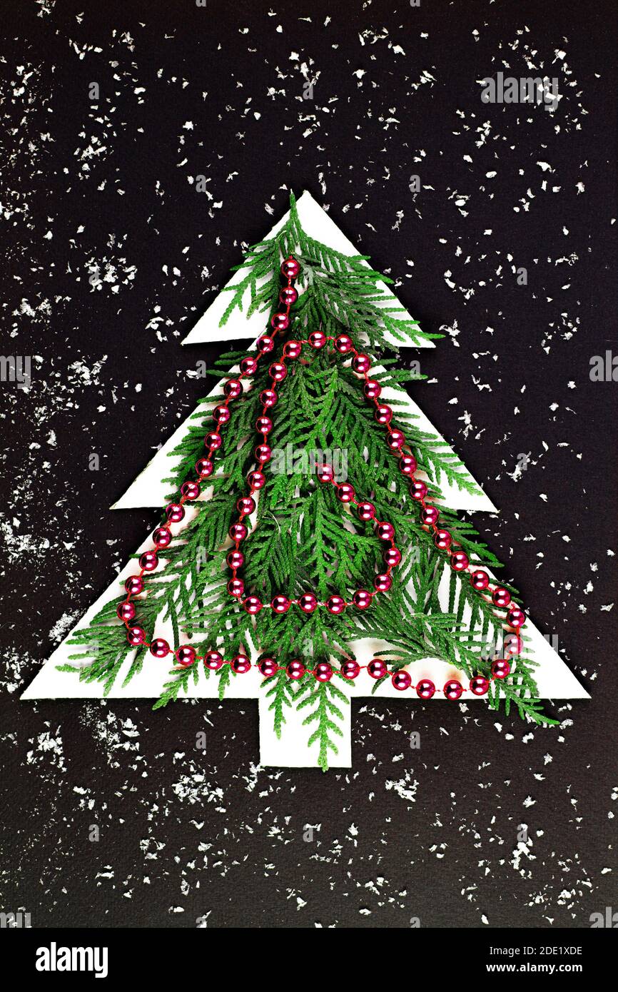 Christmas tree cut out of paper on a black background. Silhouette of a ...