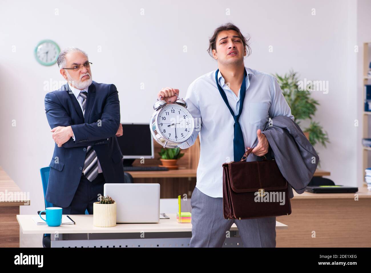 Old boss and young male employee in time management concept Stock Photo ...