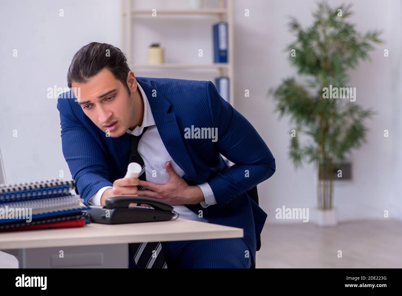Male employee suffering at workplace Stock Photo - Alamy