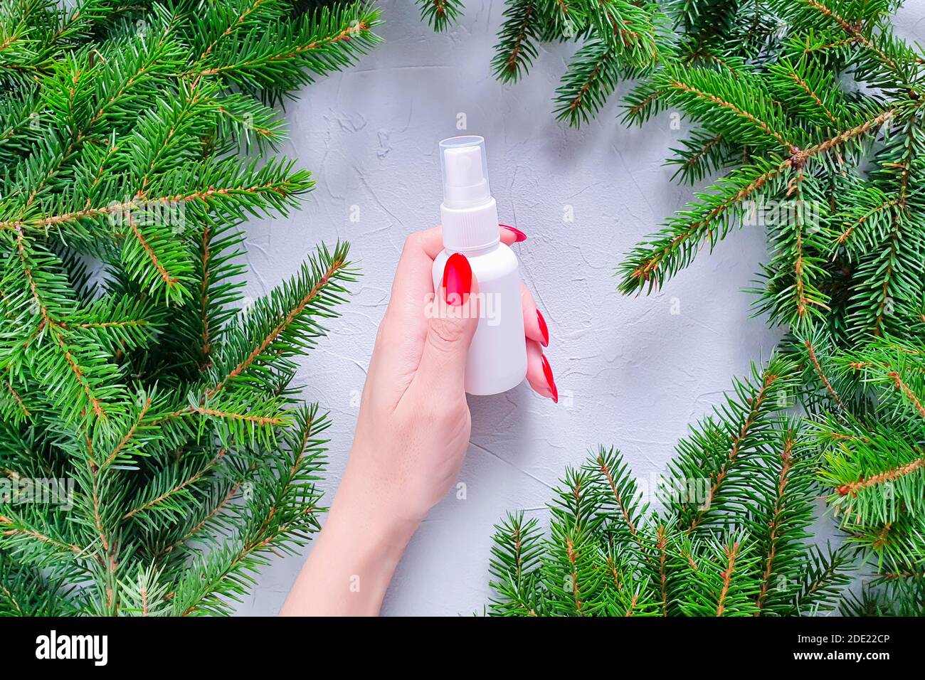 Unbranded white plastic spray bottle, female hand with red nails and ...
