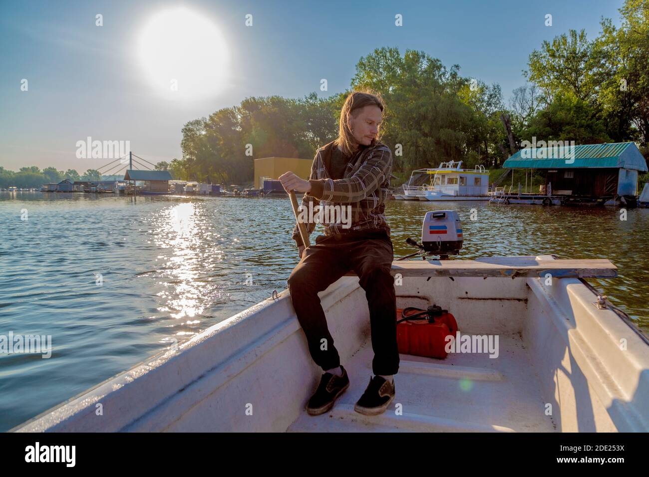 Sad and pensive mid age man with long brown hair is on his white boat ...