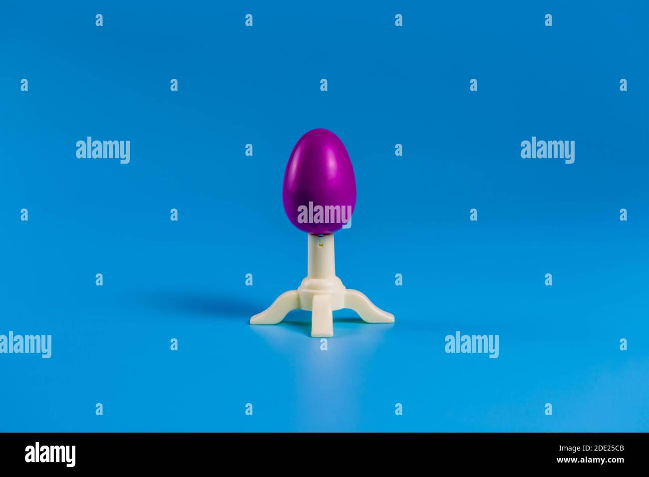 .Colored easter plastic egg on a stand in the form of a rocket on a ...