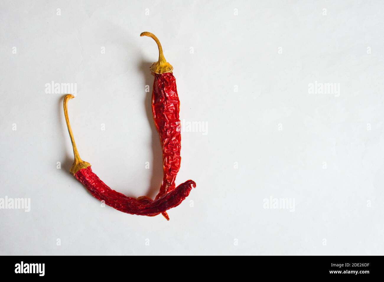 Letter J lined with red peppers on a white background. Symbol in the ...