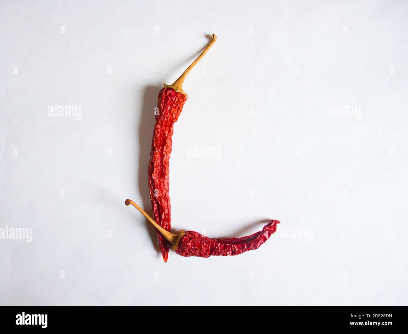 Letter L lined with red peppers on a white background. Symbol in the ...