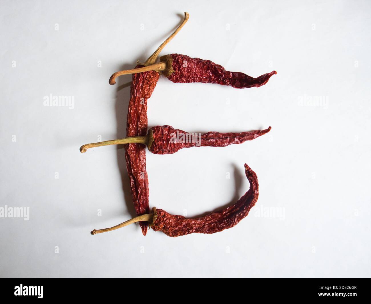 Letter E lined with red peppers on a white background. Symbol in the ...