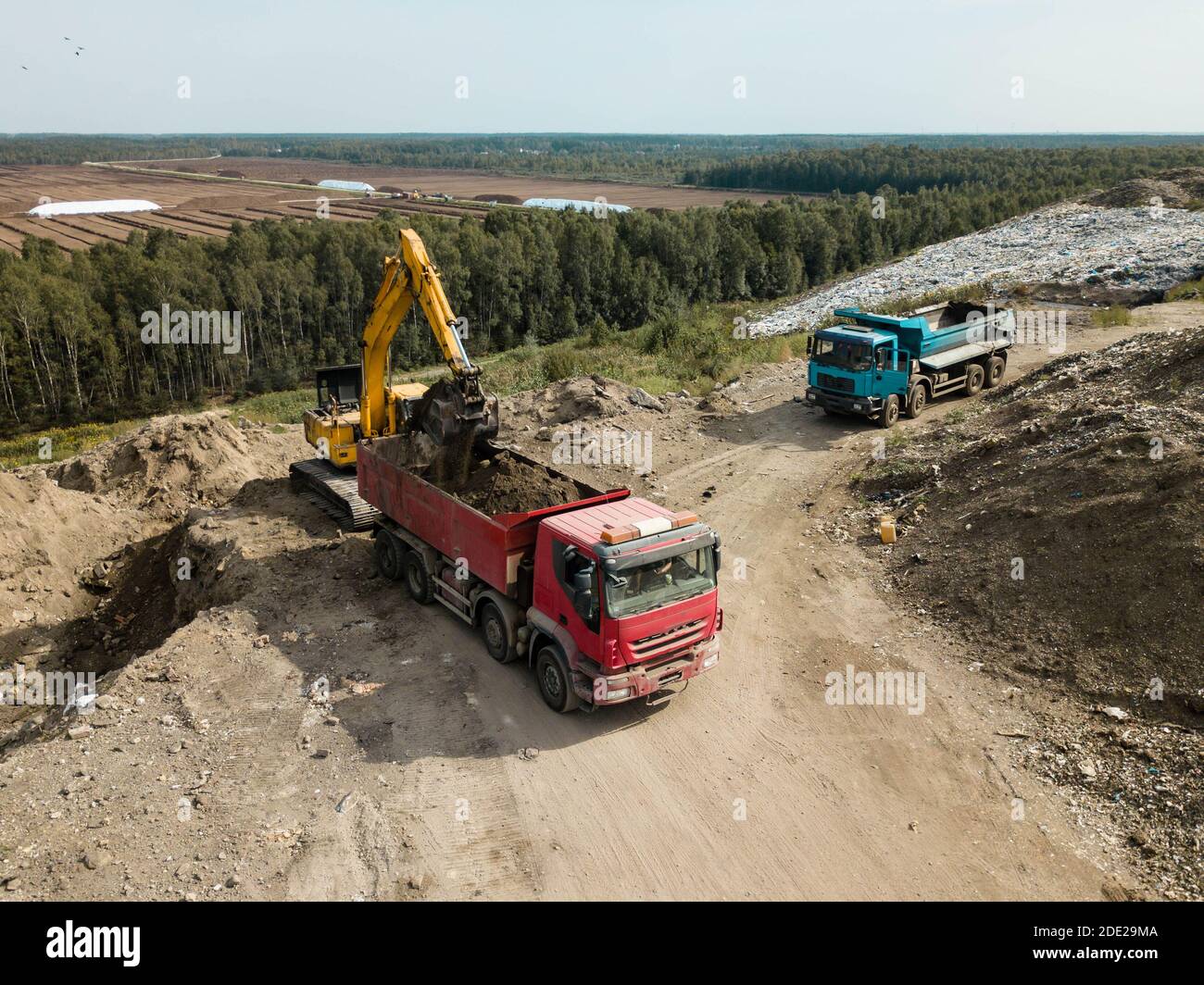 Excavation pit. Digger and trucks on dirt road. Stony soil. Heap of ...