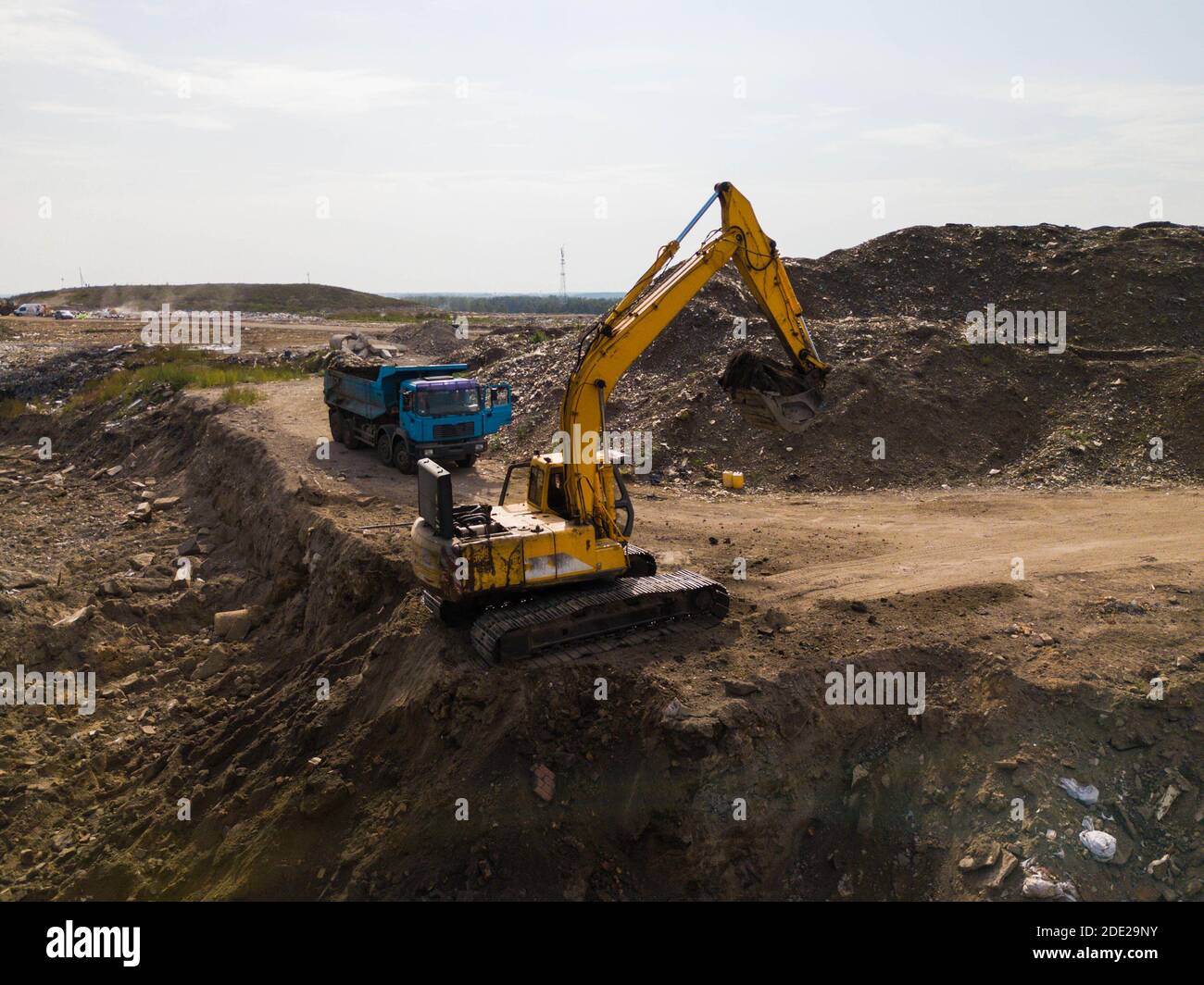 Heavy equipment on excavation pit. Yellow digger and blue truck on dirt ...