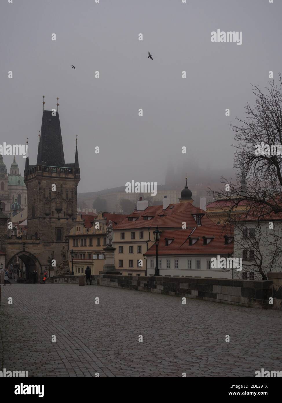 Prague Castle and Lesser Town as seen through the fog frm Charles Bridge in Prague on an autumn ...