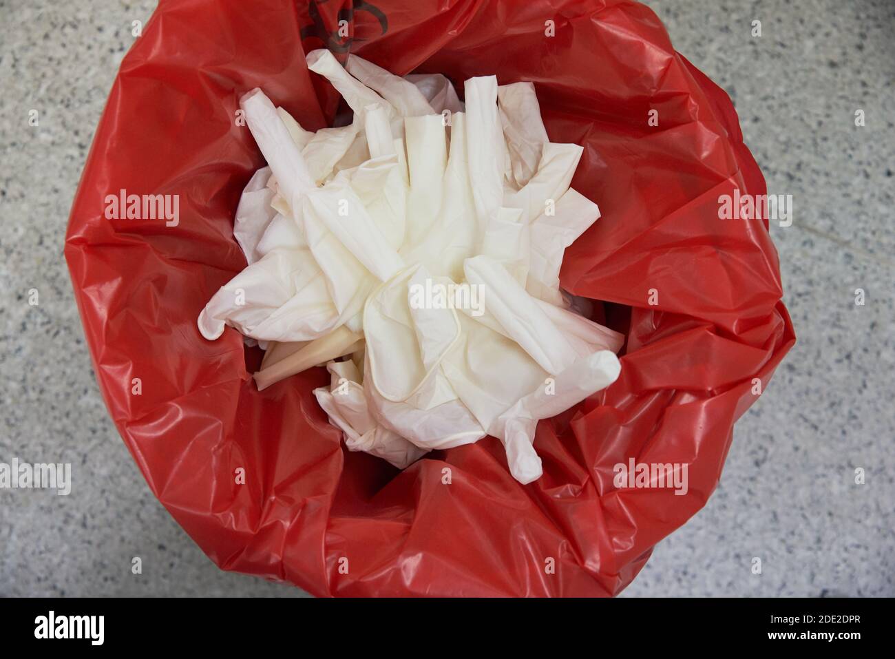 Top view of used surgical gloves in a red garbage bin for biohazard ...